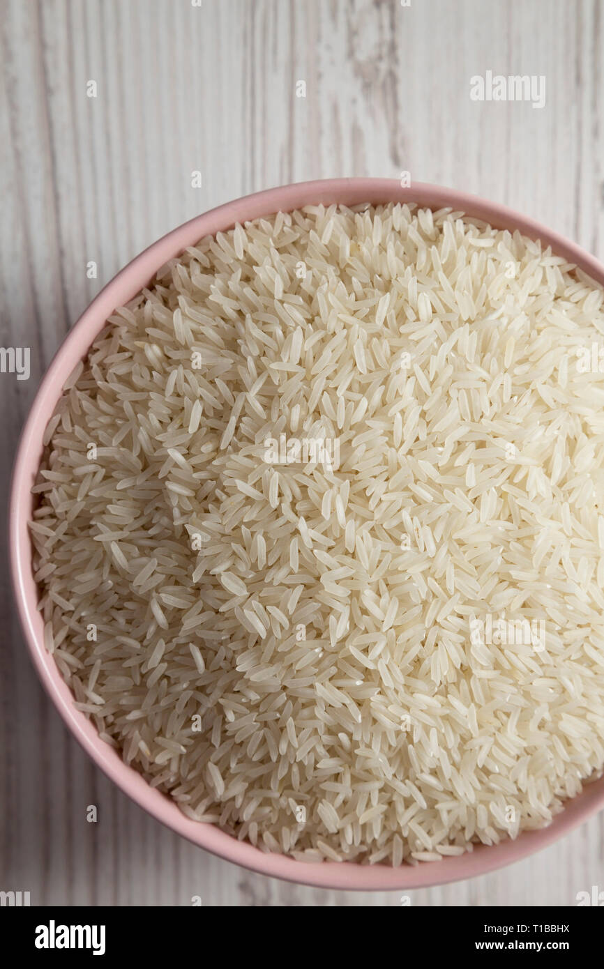 Dry white rice basmati in a pink bowl over white wooden background ...
