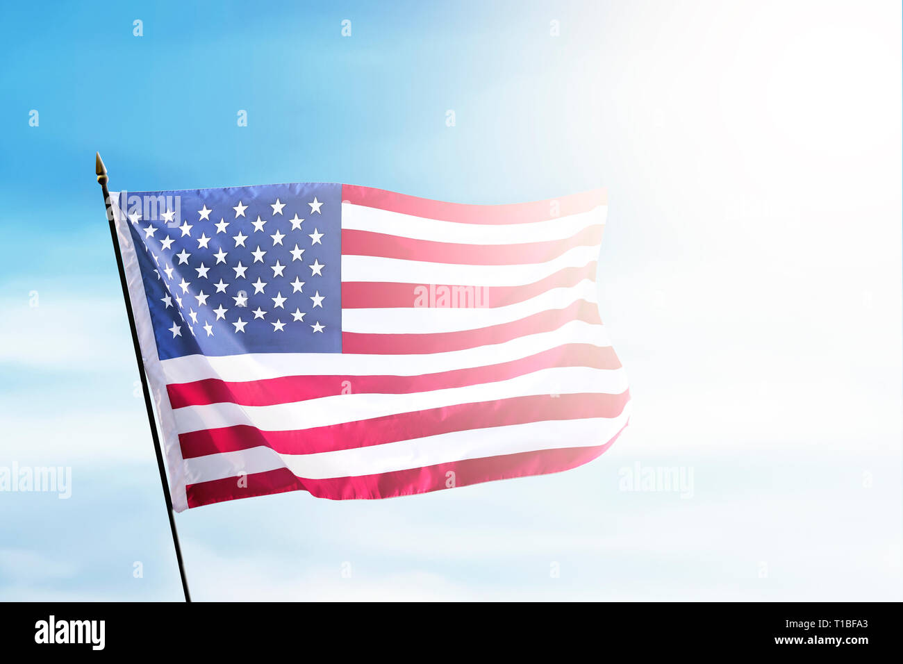 Black pole with American flag waving on the blue sky background. Labor ...