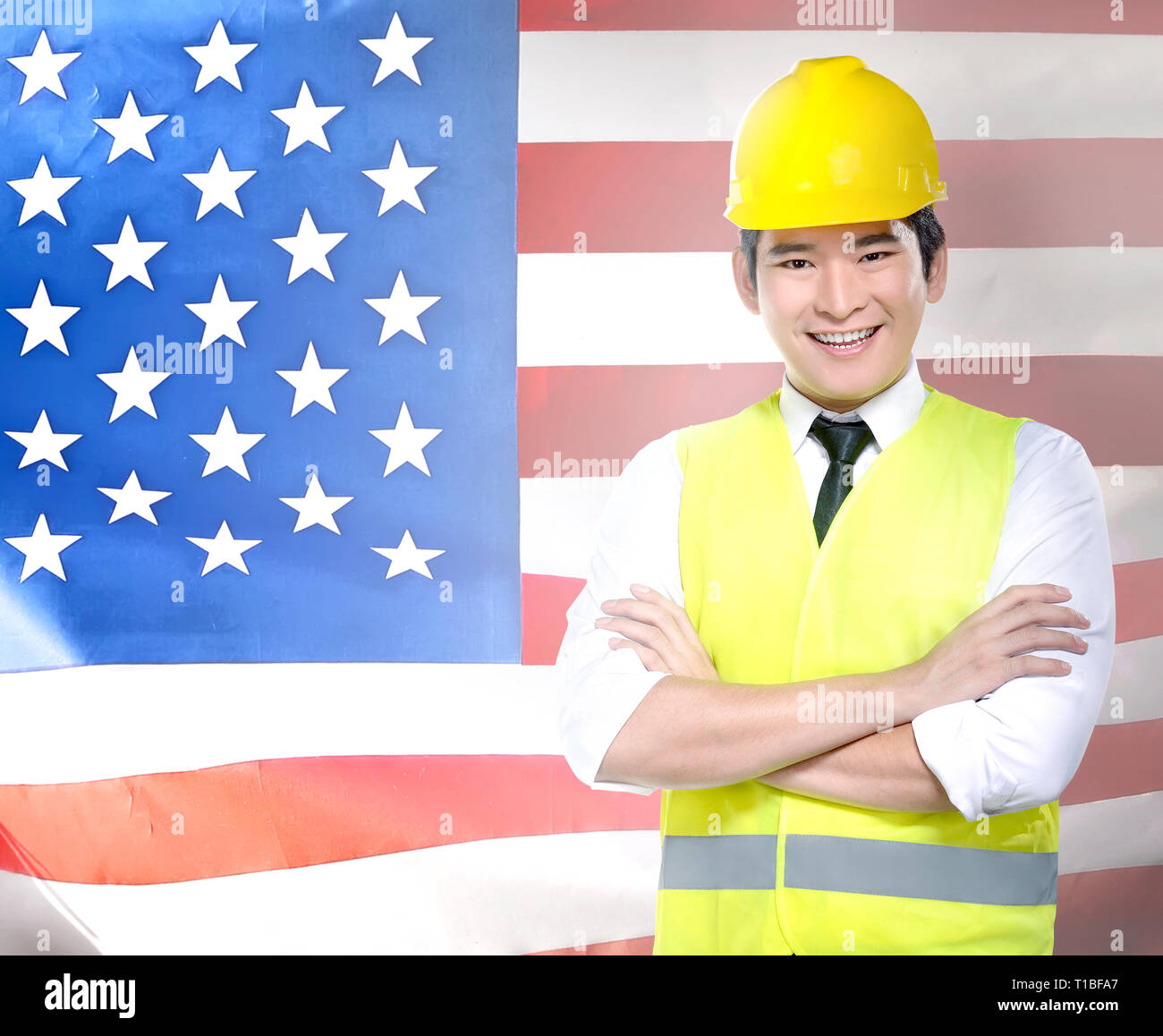 Smiling asian worker man in safety vest and yellow helmet standing with ...