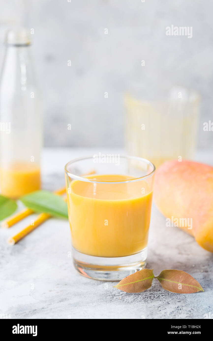 Tropical Mango smoothie in a glass and fresh mango on a light ...