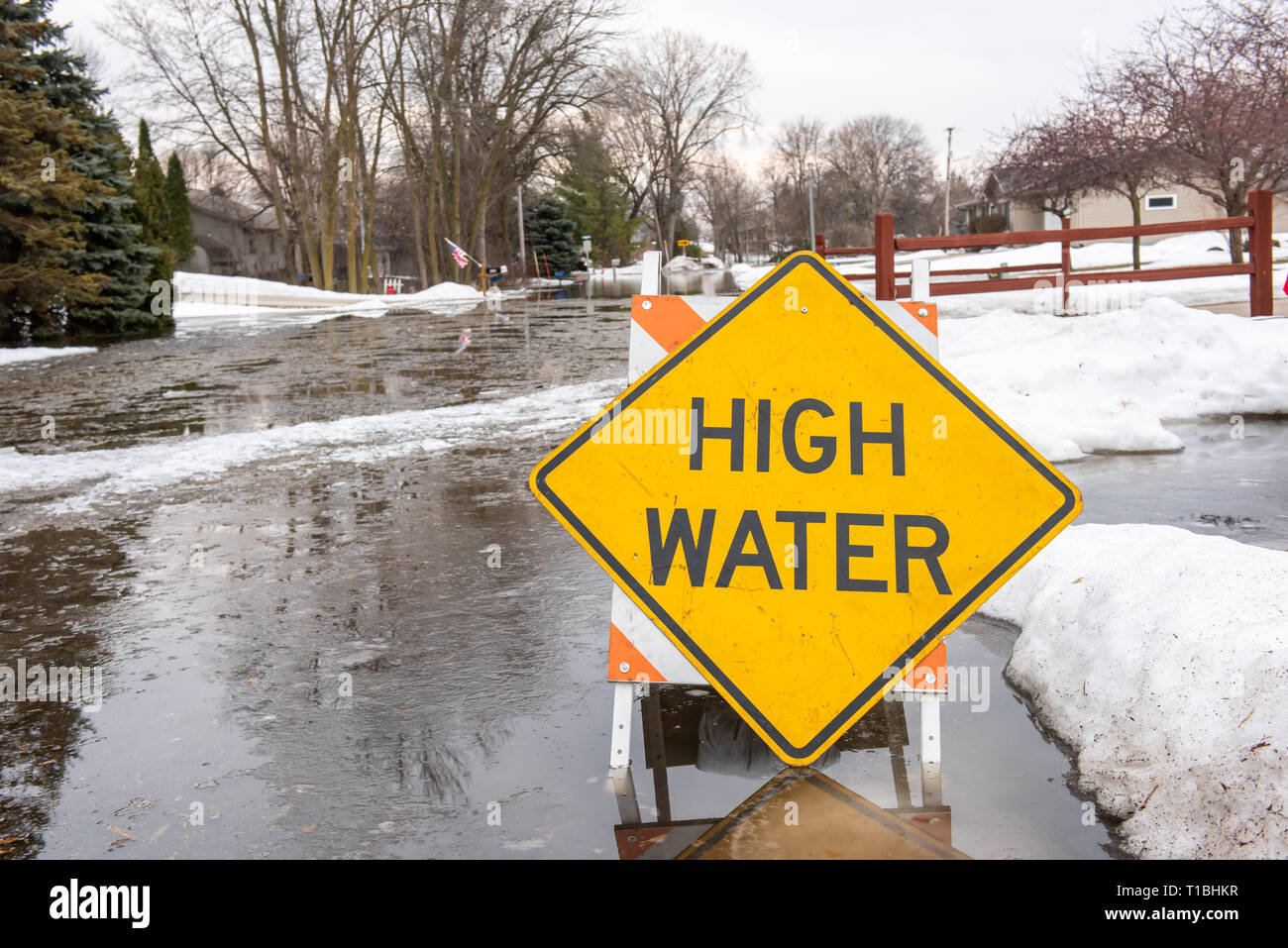 A high water sign is sitting in a flooded street after a heavy rain and ...