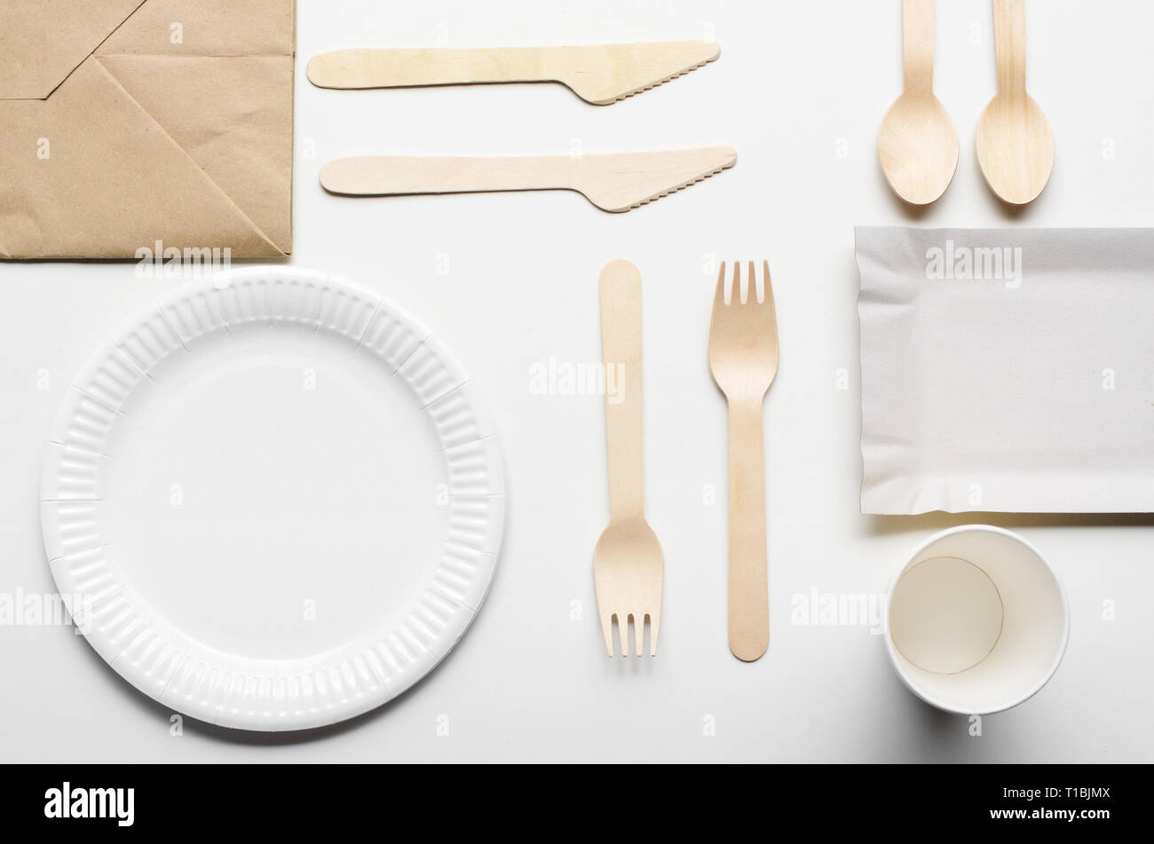 Wooden single use kitchenware and paper shopping bag on white. Top view ...