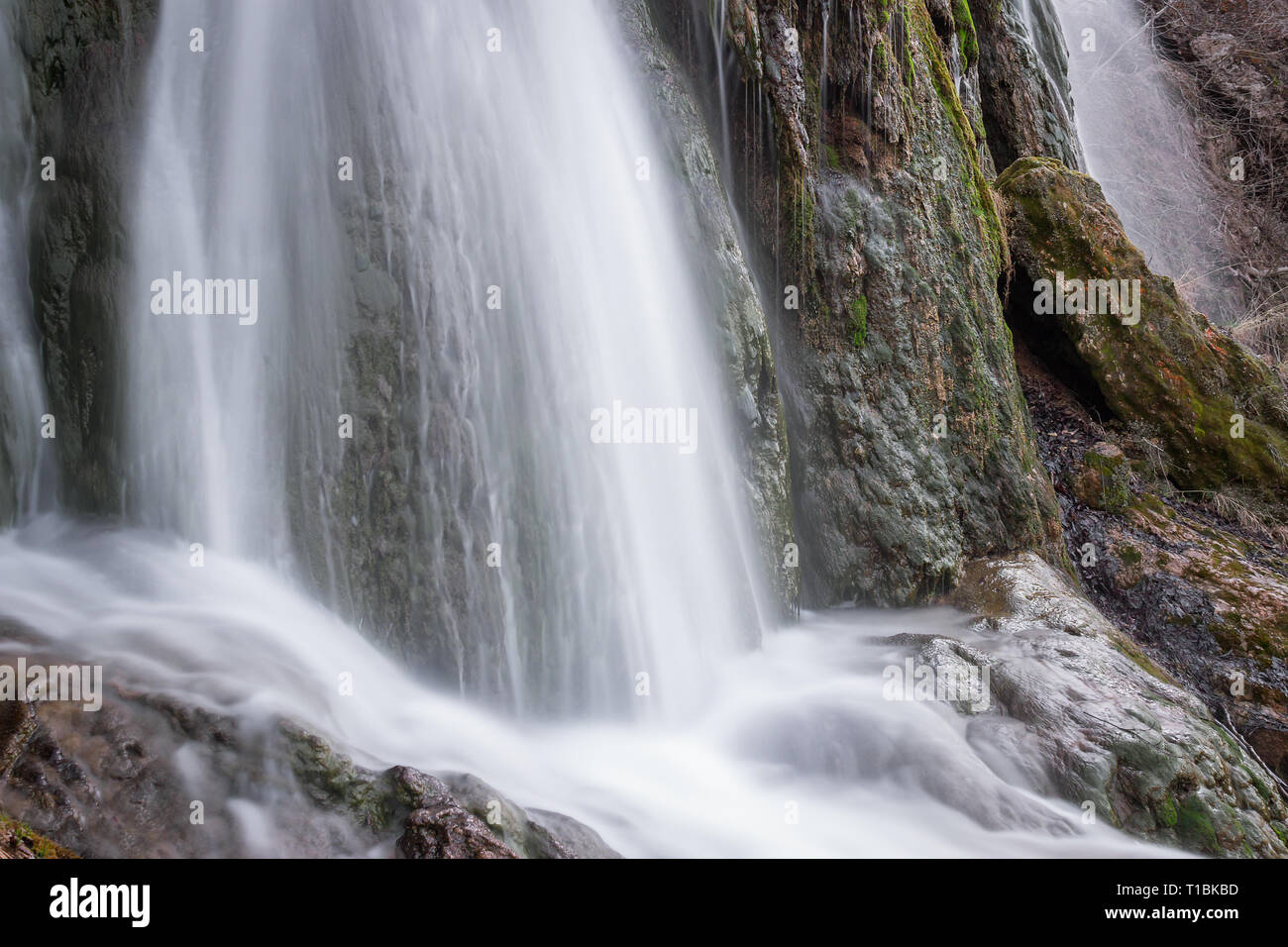 Close up, long exposure view of a sunlit waterfall with soft streams of ...