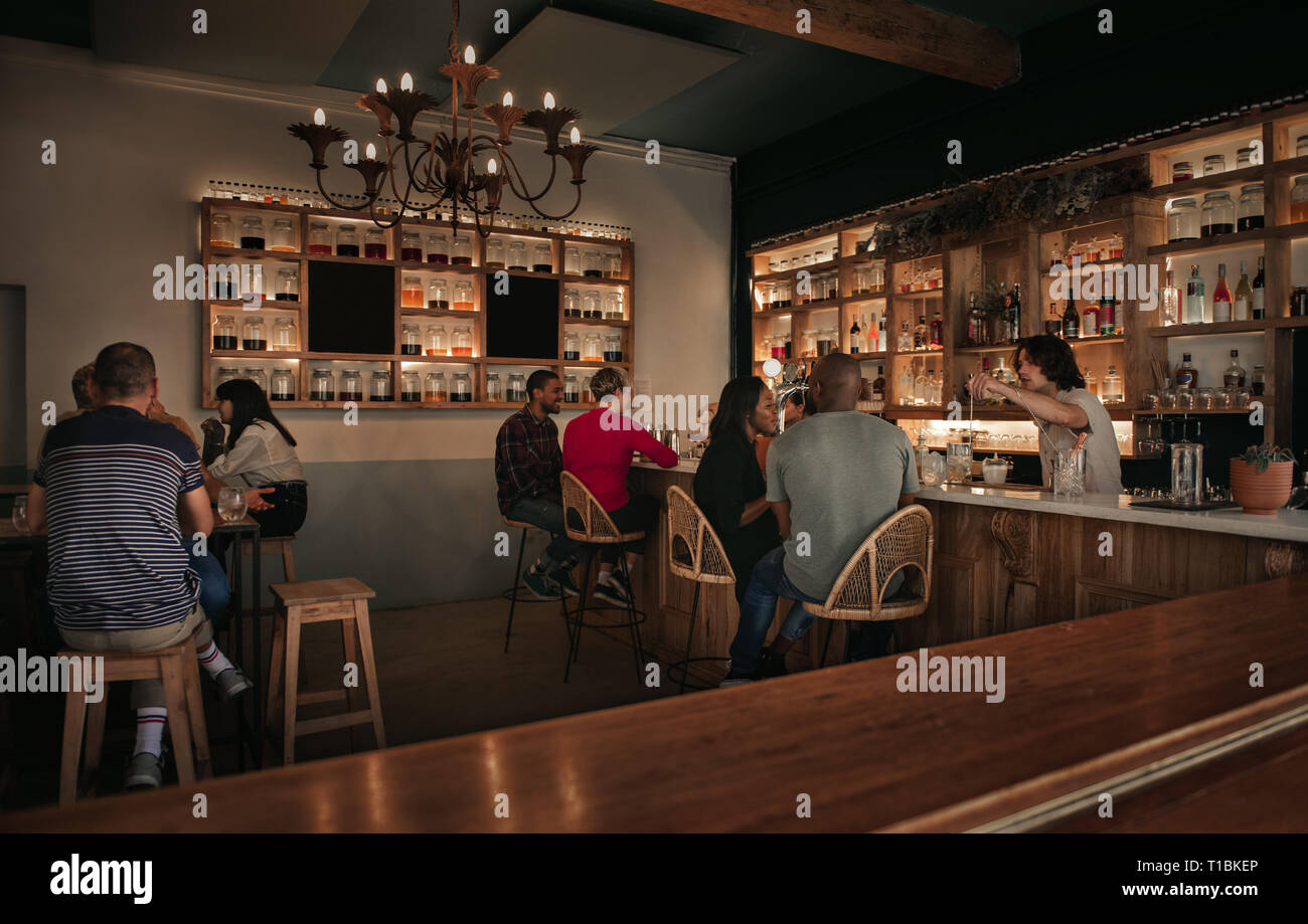 Diverse young people having drinks in a bar at night Stock Photo - Alamy