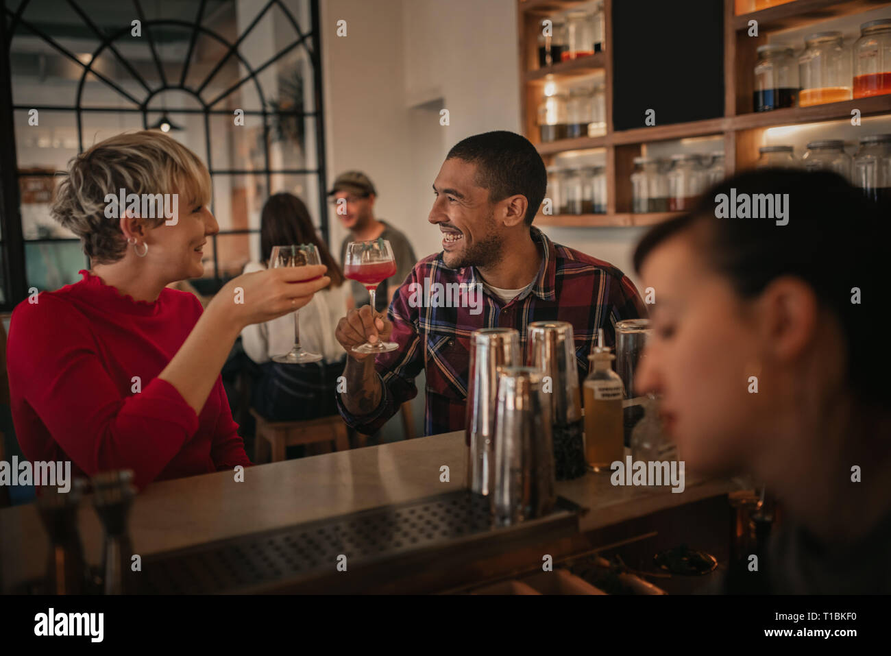 Laughing friends having drinks together in a bar at night Stock Photo ...