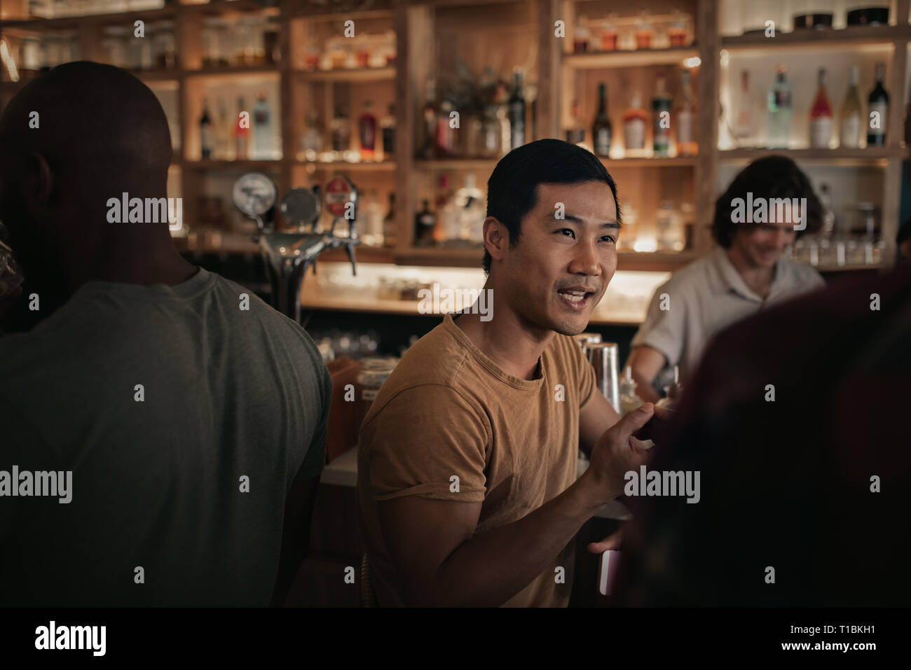 Young man talking with friends in a busy bar Stock Photo - Alamy
