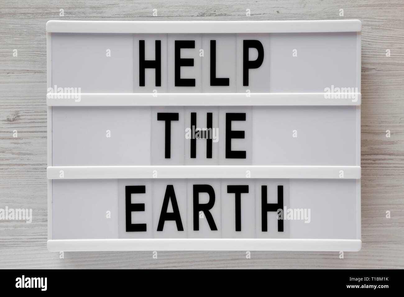 'Help the Earth' words on lightbox over white wooden background, top ...