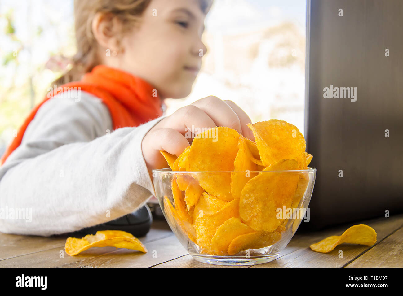 child with chips behind a computer. selective focus. food Stock Photo ...