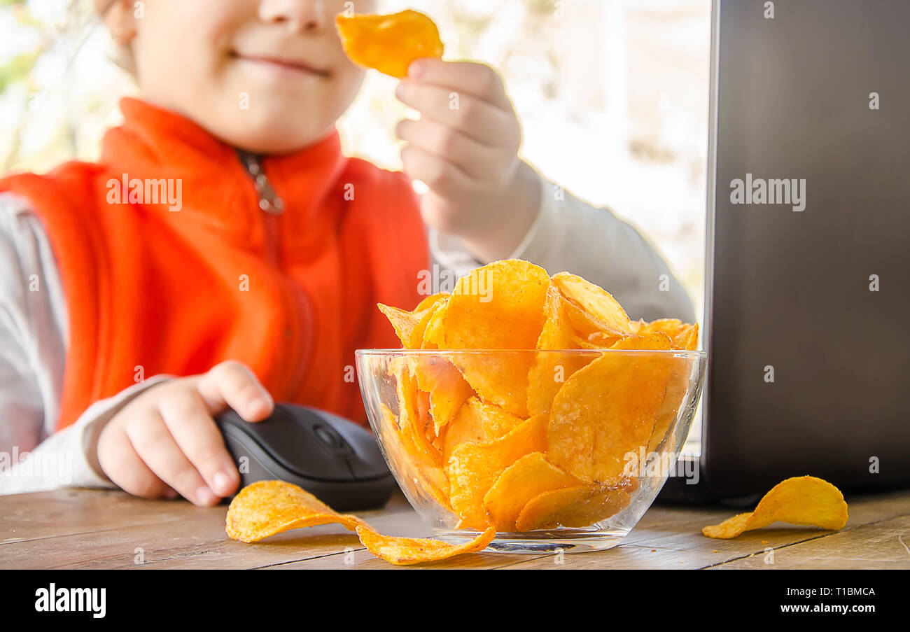 child with chips behind a computer. selective focus. food Stock Photo ...