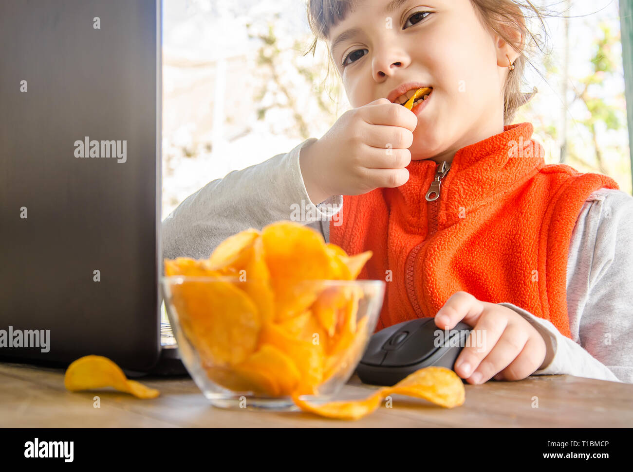 child with chips behind a computer. selective focus. food Stock Photo ...