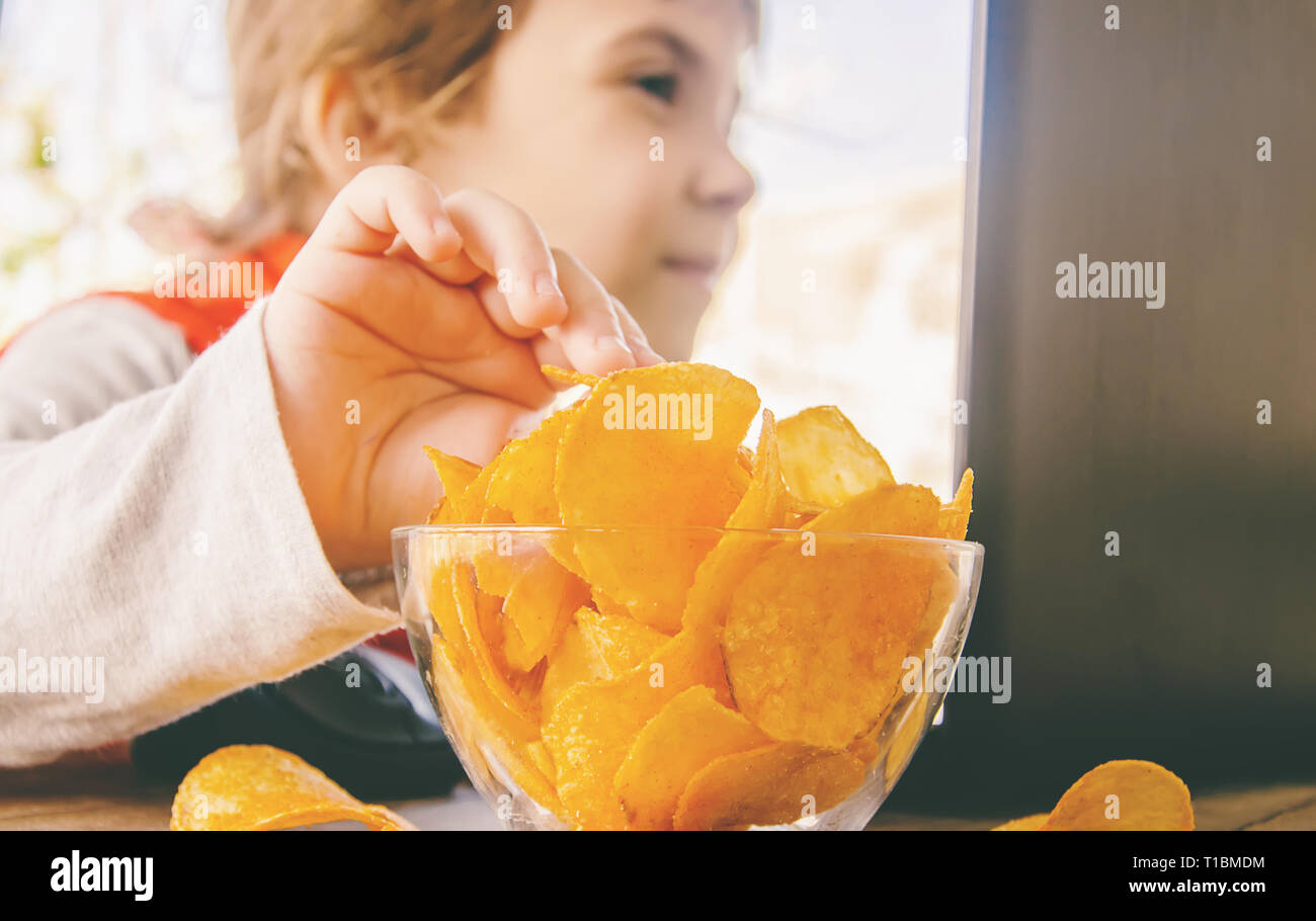 child with chips behind a computer. selective focus. food Stock Photo ...
