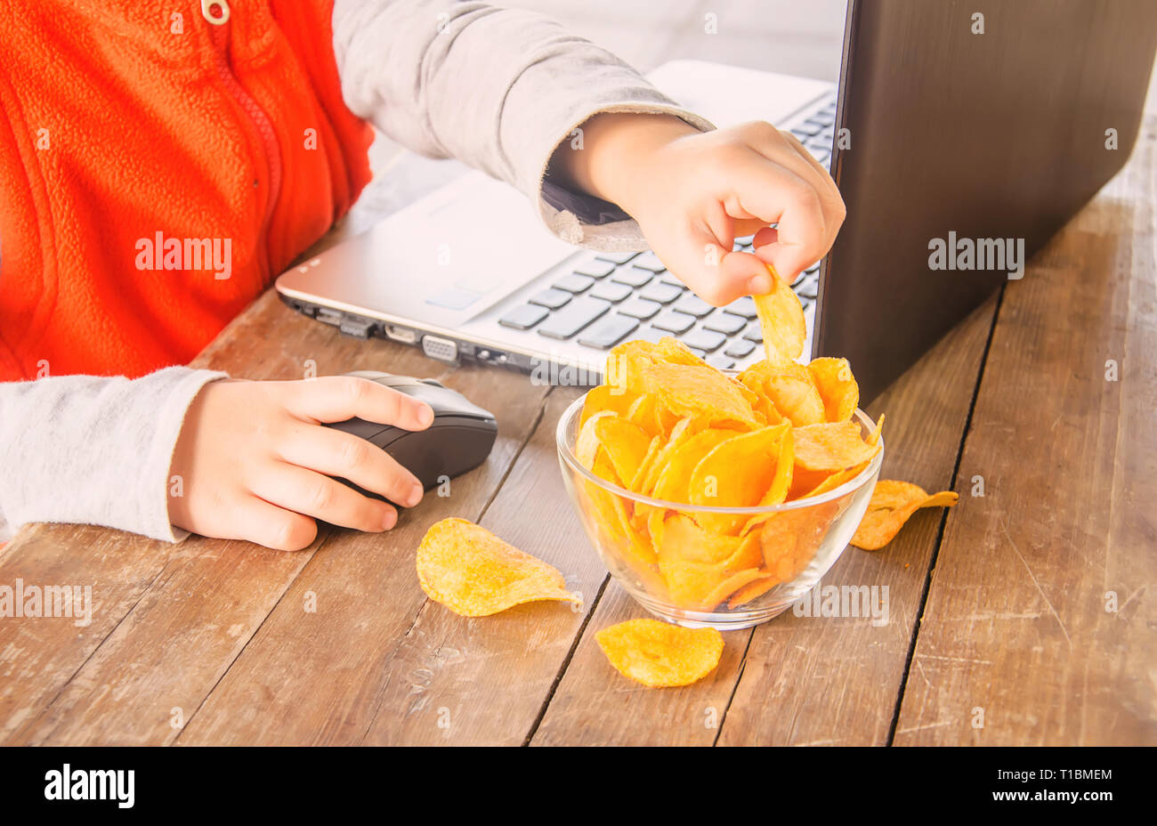 child with chips behind a computer. selective focus. food Stock Photo ...
