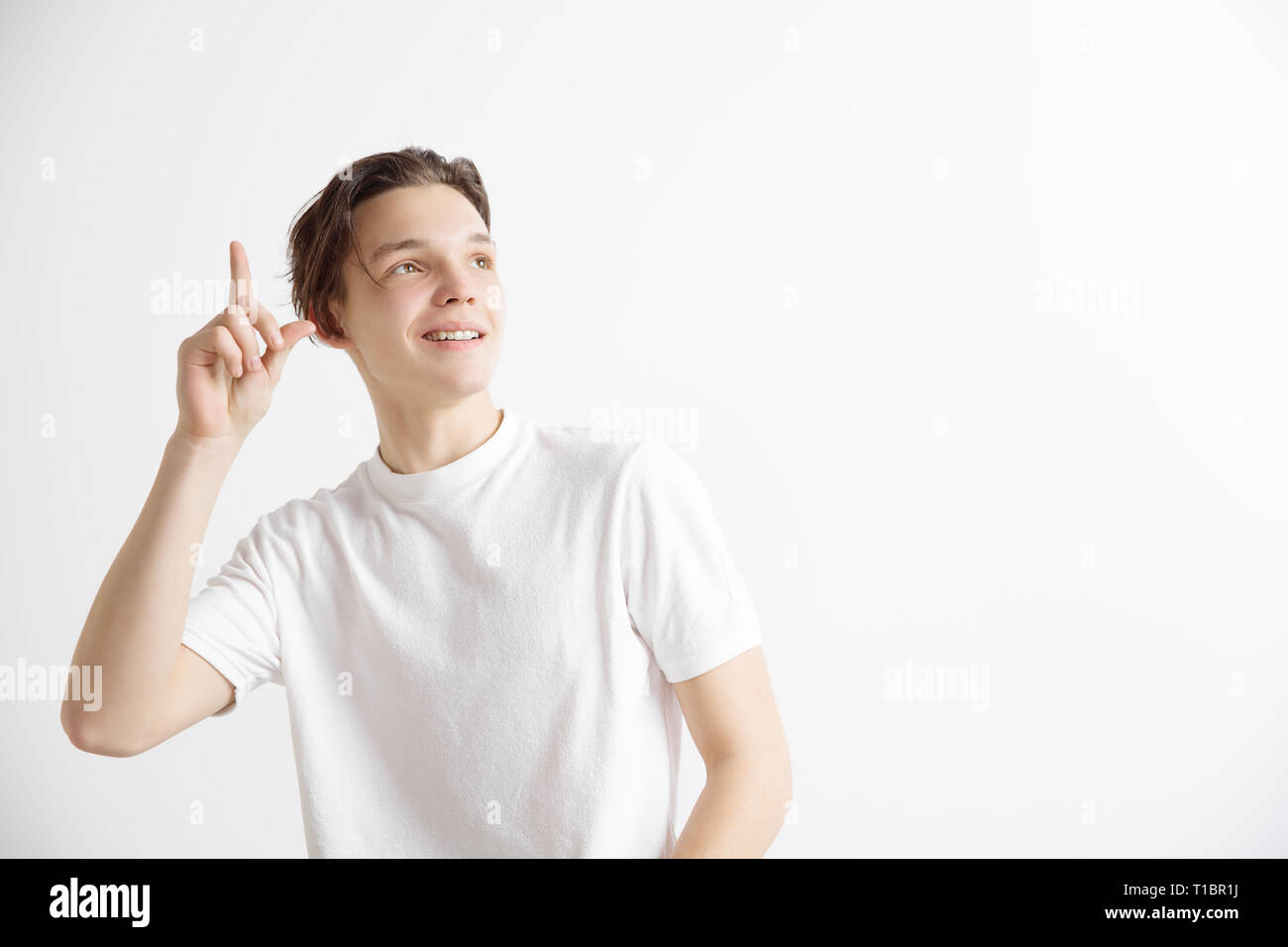 Happy student standing, smiling, pointing up isolated on gray studio ...