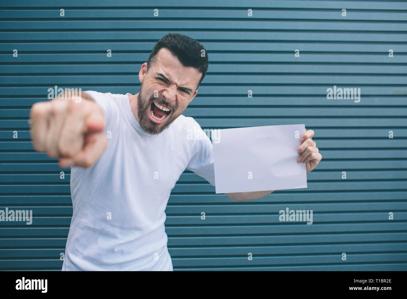 Guy is standing and posing. He is looking and pointing on camera. Also ...