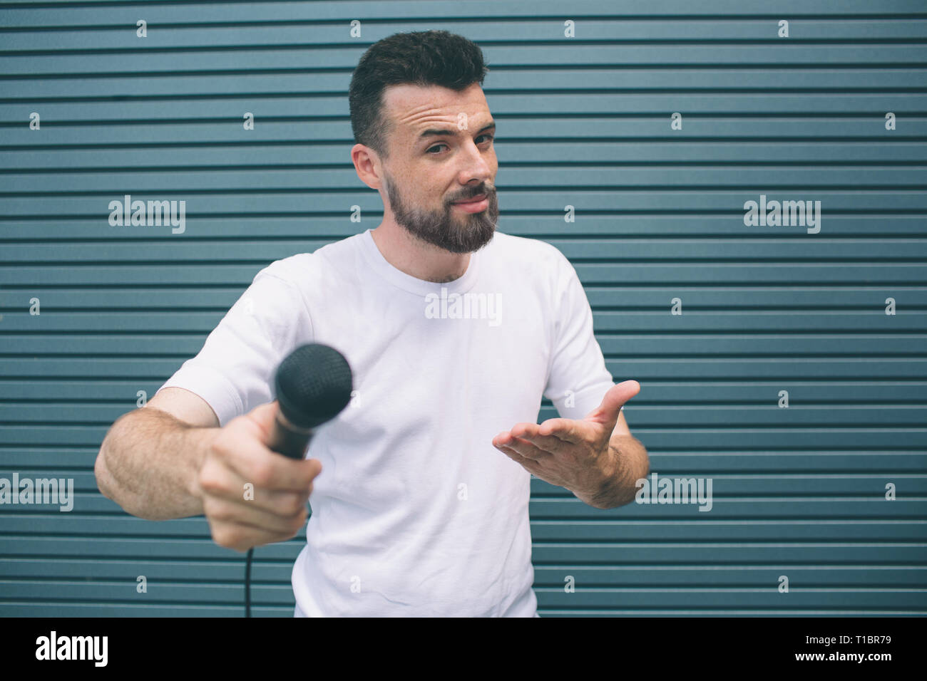 Positive singer is holding microphone in hands. He is looking at camera ...