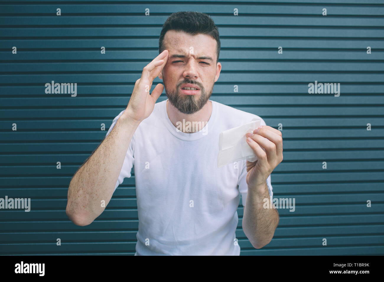 Young man is holding tissue in one hand and holding another one close ...