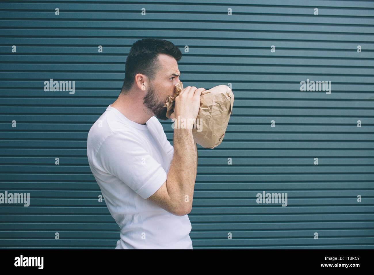 A picture of man blowing paper bag. He feels bad. Guy is going to vomit ...
