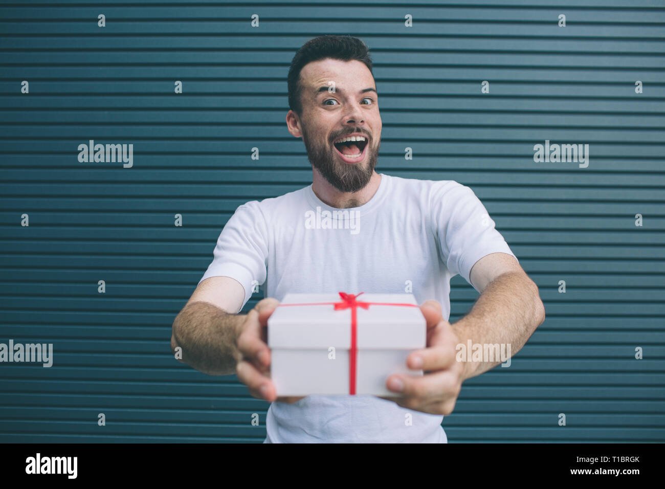 Happy man is holding present in hands. He is looking on camera and ...