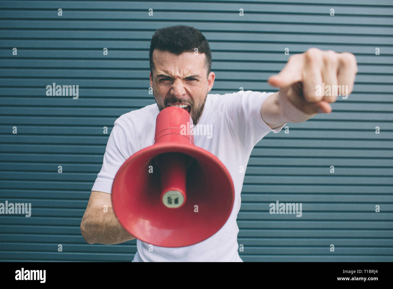 Serious guy is screaming in megaphone. He is holding it with one hand ...