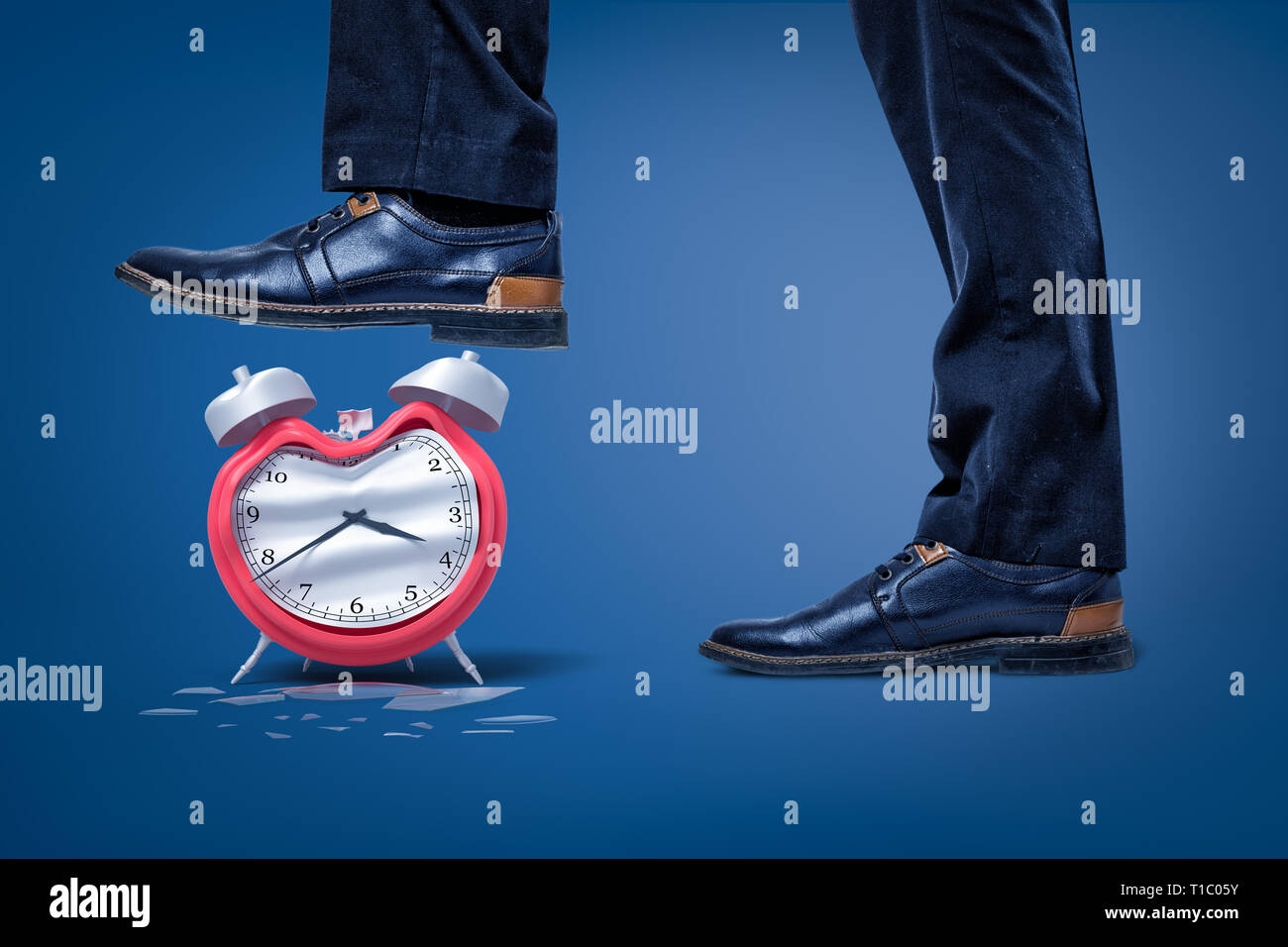 Side close-up of man's feet, one foot raised to crush broken bent alarm ...