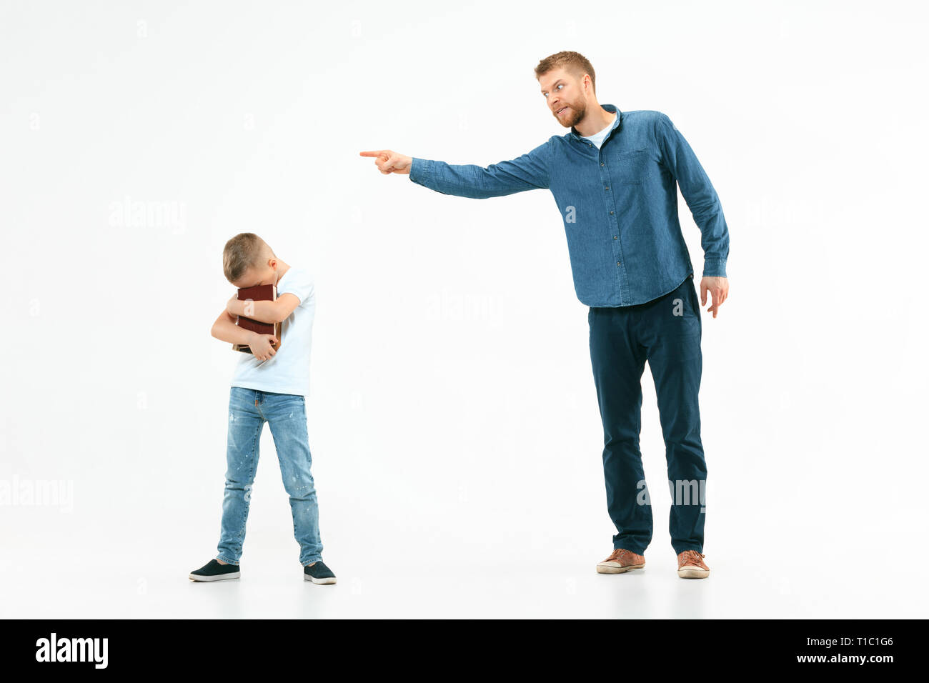 Angry father scolding his son at home. Studio shot of emotional family ...