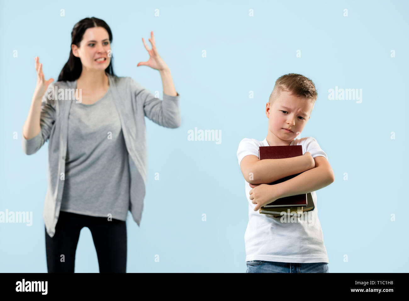 Angry mother scolding her son at home. Studio shot of emotional family ...