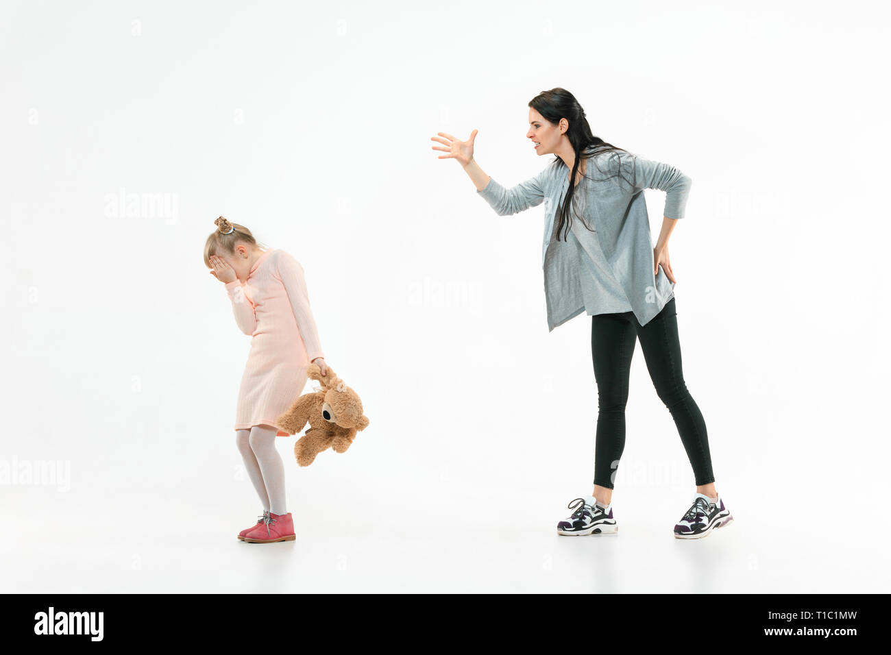 Angry mother scolding her daughter at home. Studio shot of emotional family. Human emotions ...