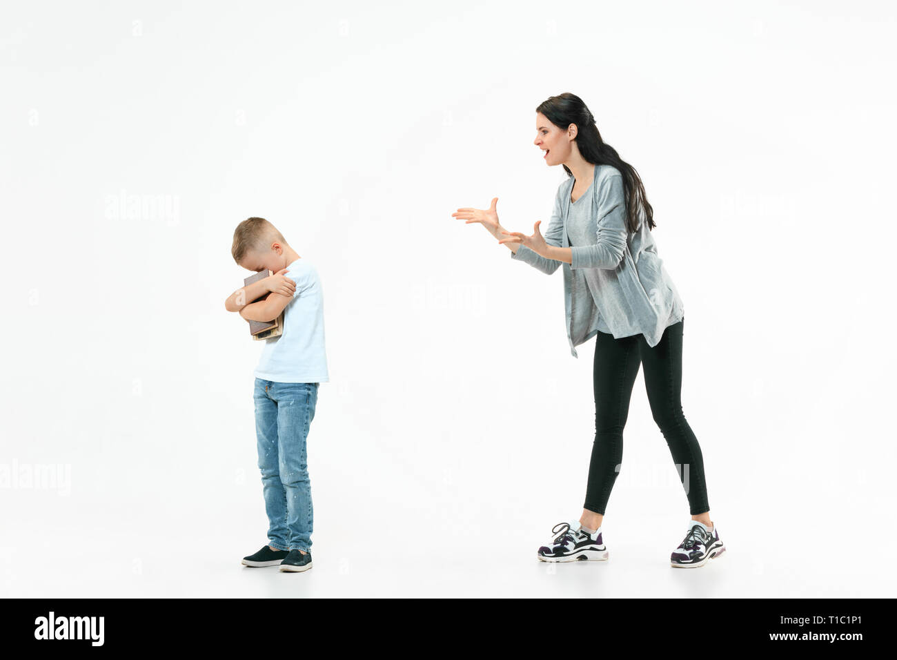 Angry mother scolding her son at home. Studio shot of emotional family ...