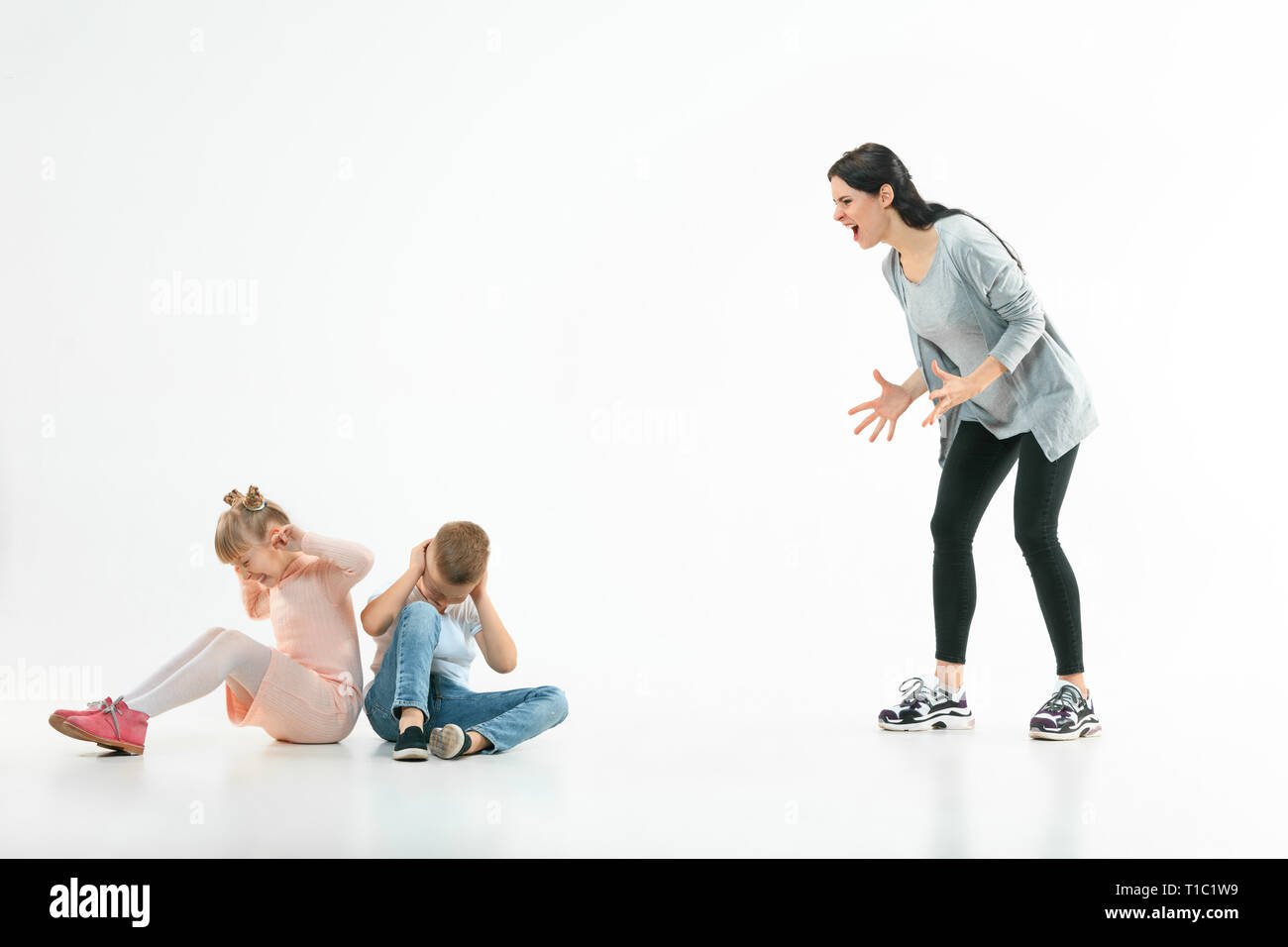 Angry mother scolding her son and daughter at home. Studio shot of ...