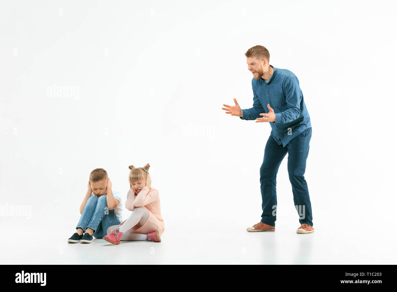 Angry father scolding his son and daughter at home. Studio shot of ...