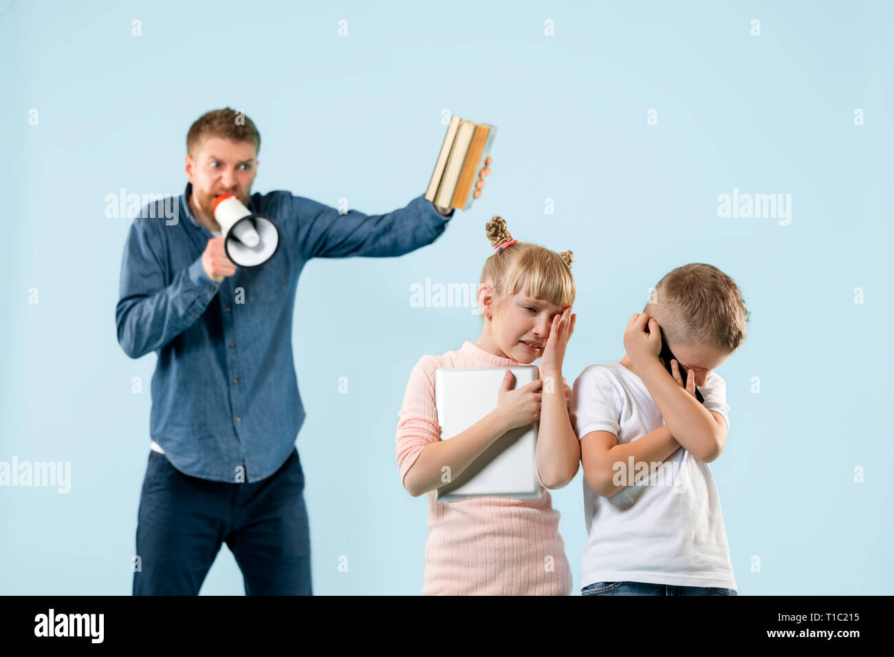 Angry father scolding his son and daughter at home. Studio shot of ...