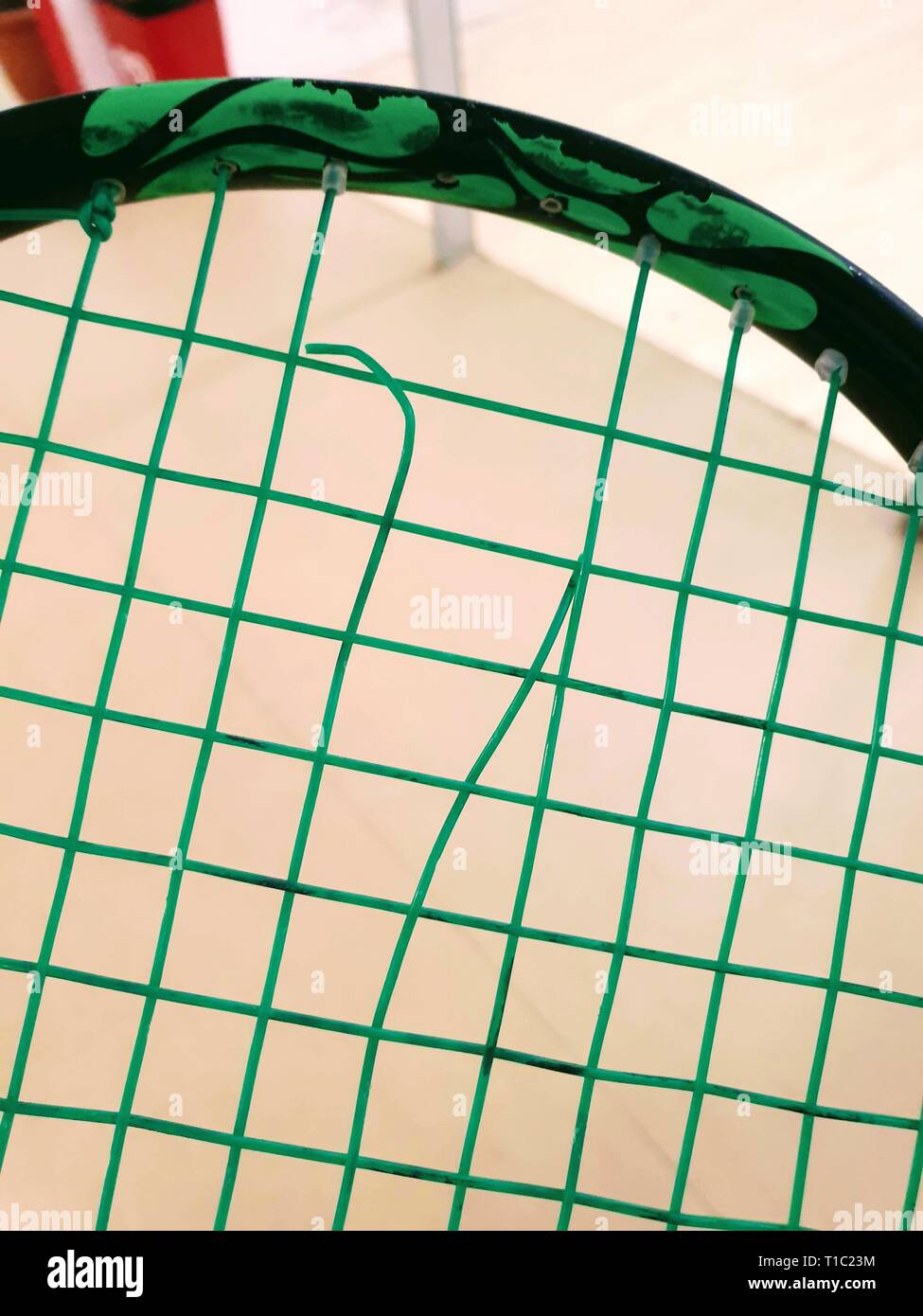 Squash racket with torn string with squash court at the background ...