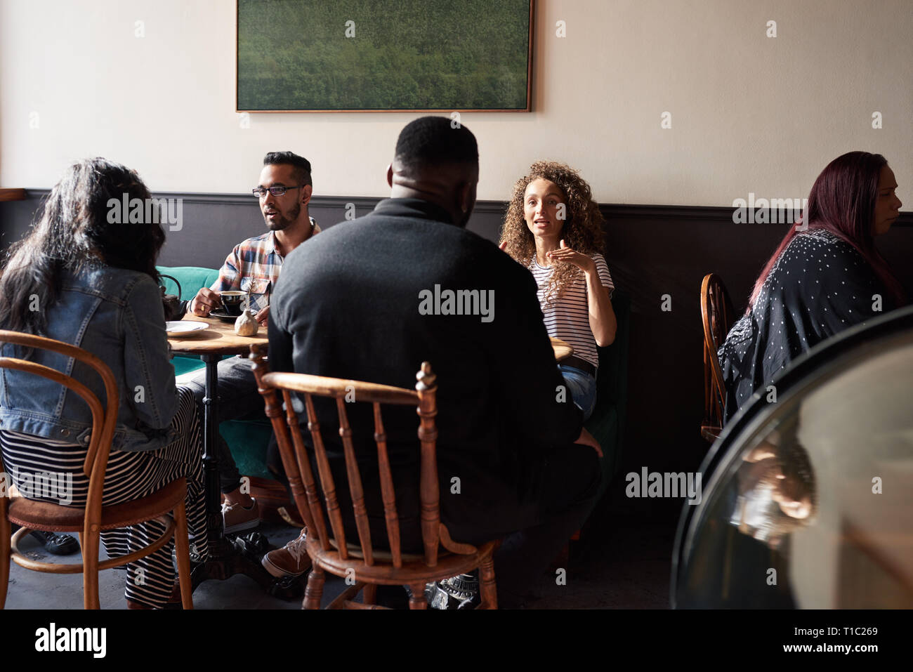Diverse friends talking over coffee while sitting in a cafe Stock Photo ...