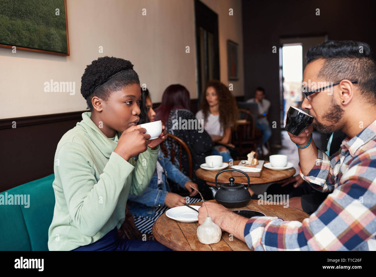 Multiethnic young couple talking over drinks in a cafe Stock Photo - Alamy