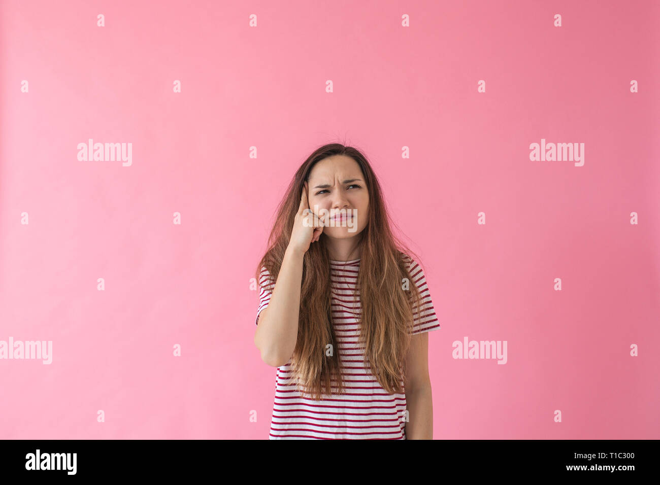 A portrait on a pink background of a girl who thinks about something or ...