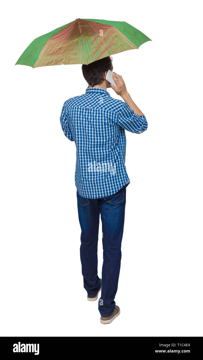 backview of man walking with a mobile phone under an umbrella. backside ...