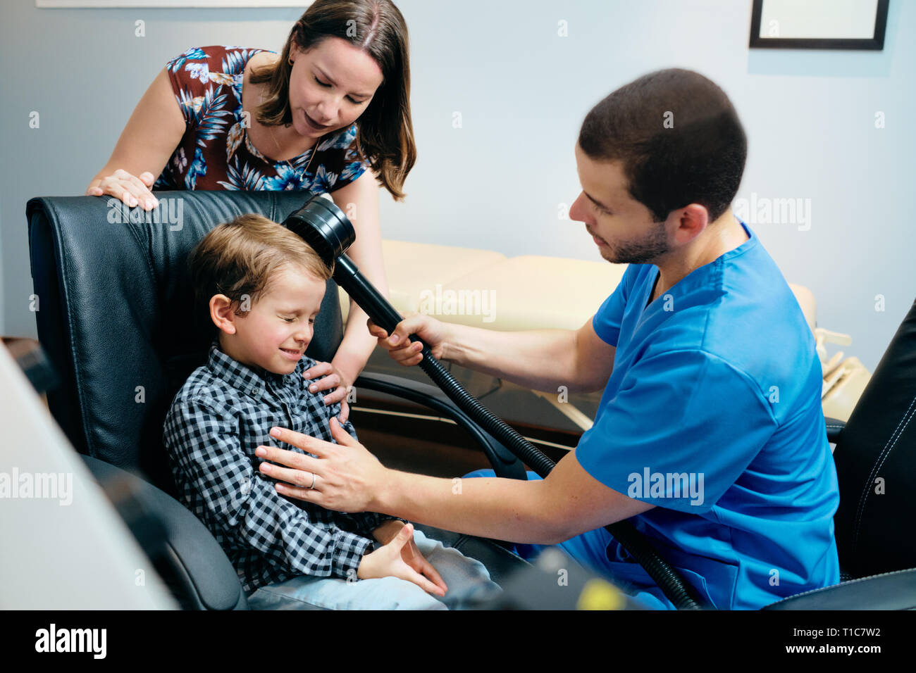 Paediatrician Doctor Doing Brain Treatment To Autistic Child In Clinic ...