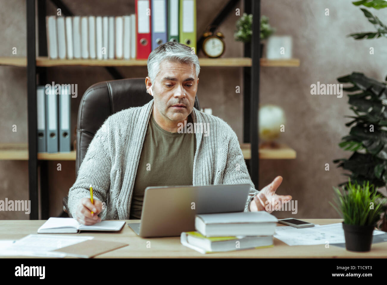 Serious nice man taking notes in the notebook Stock Photo - Alamy