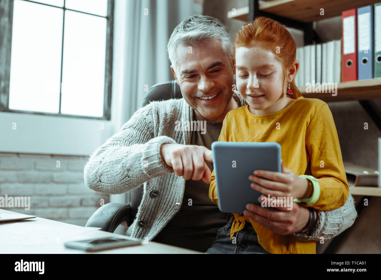 Joyful good looking man showing the tablet to his daughter Stock Photo ...
