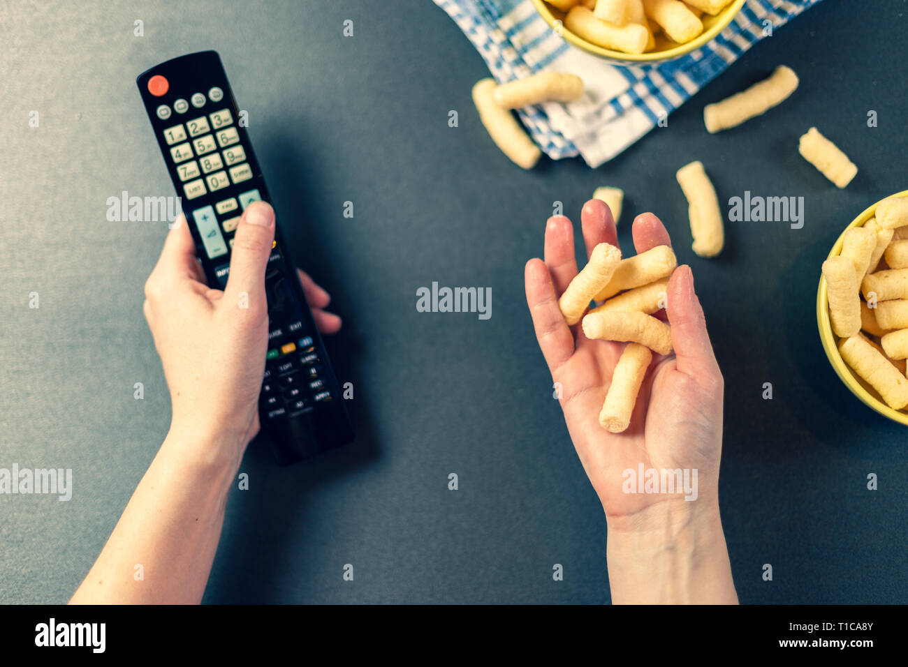 Person with TV remote watching a tv and eating chips, top view Stock ...