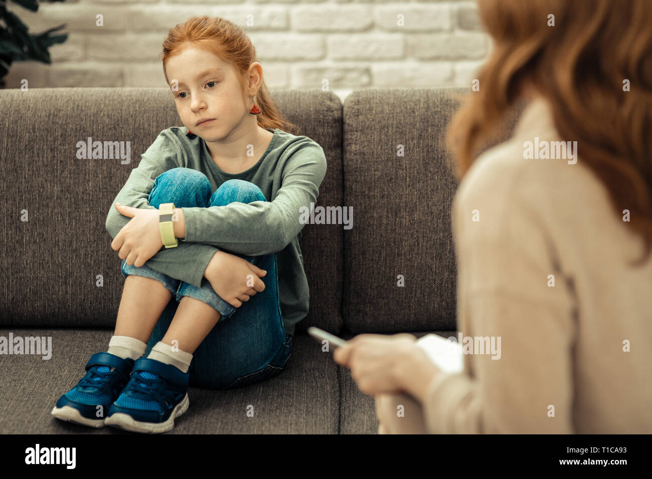 Sad cheerless girl sitting on the sofa Stock Photo - Alamy