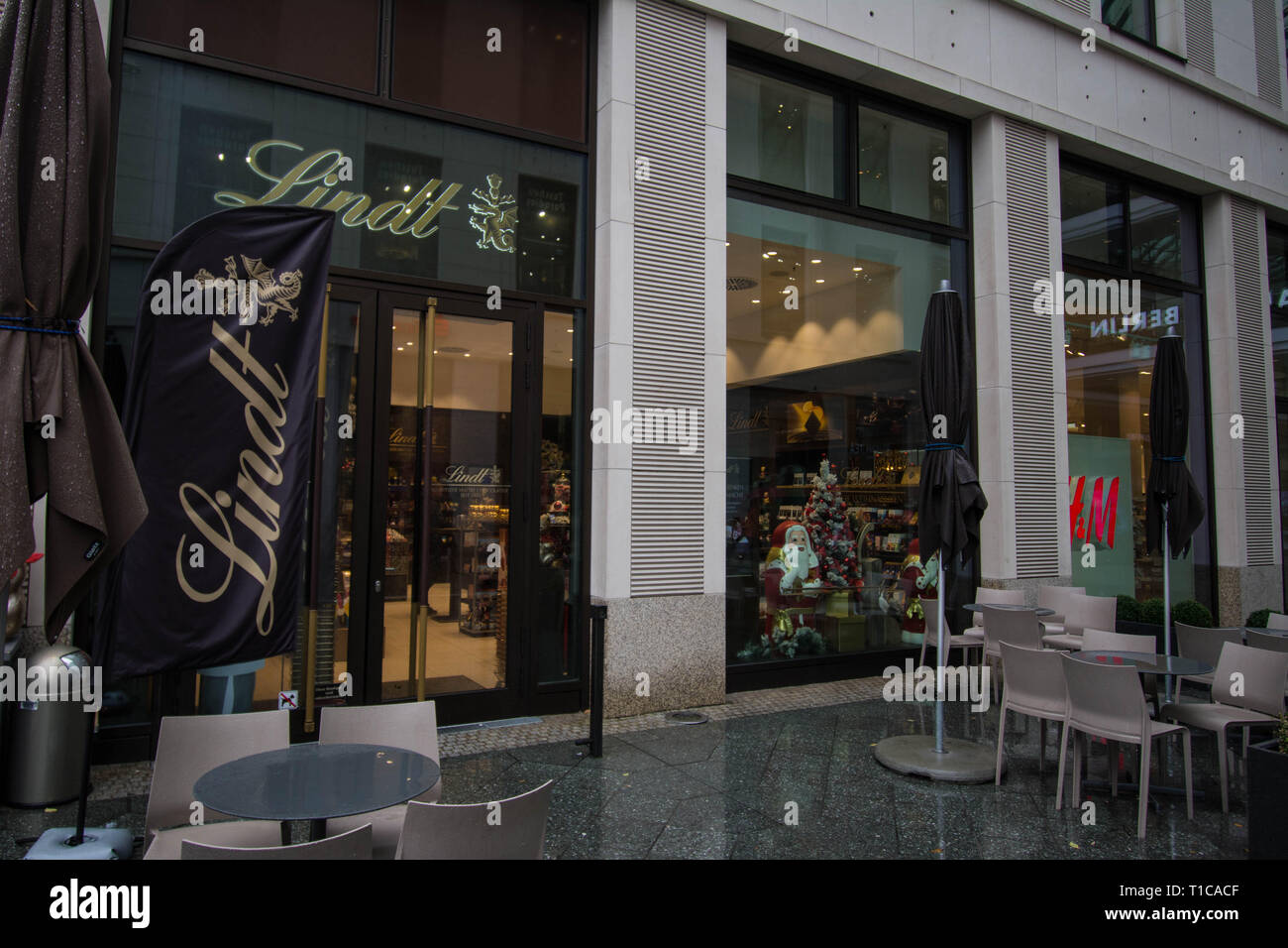Lindt shop and sign in Berlin Germany and cafe with seats outside sign ...