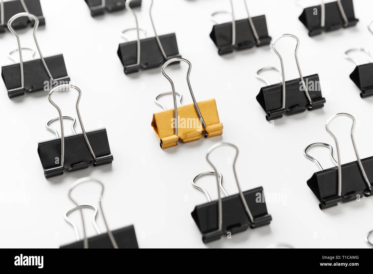 Golden binder clip standing between black ones Stock Photo - Alamy