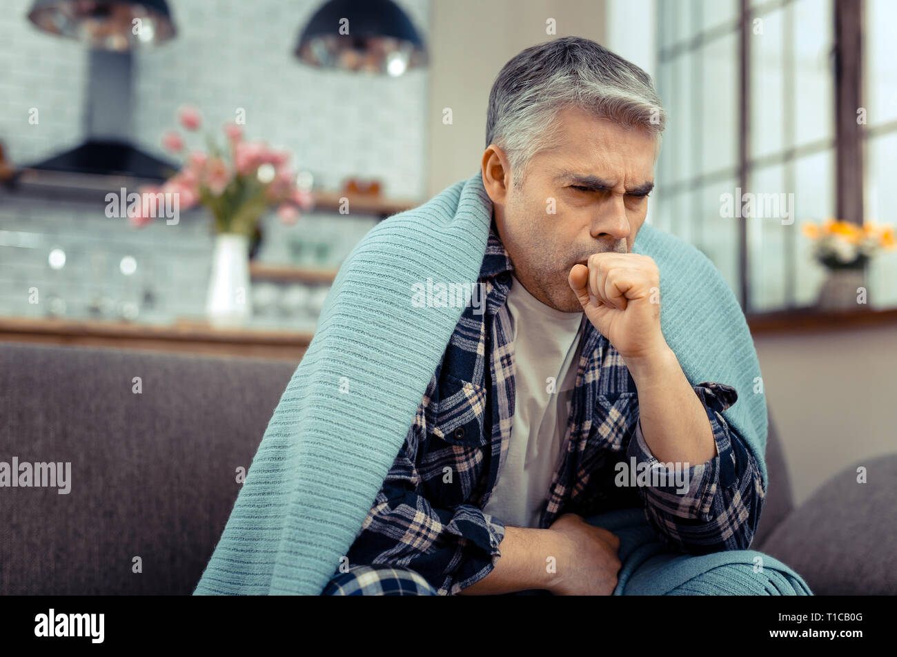 Unhappy cheerless man coughing into his hand Stock Photo - Alamy
