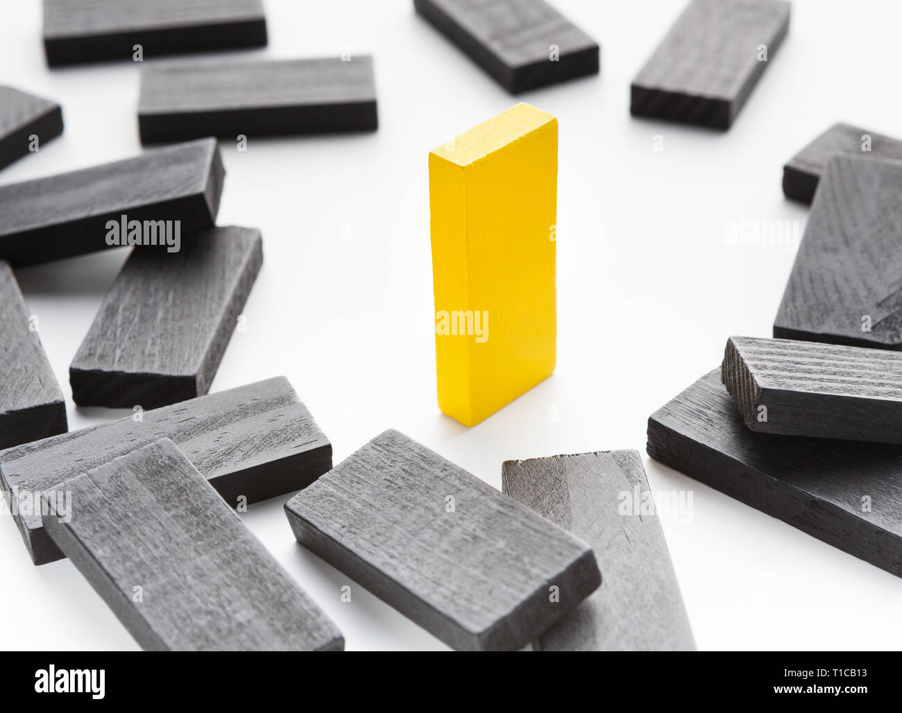 One yellow wooden block standing among fallen black ones Stock Photo ...