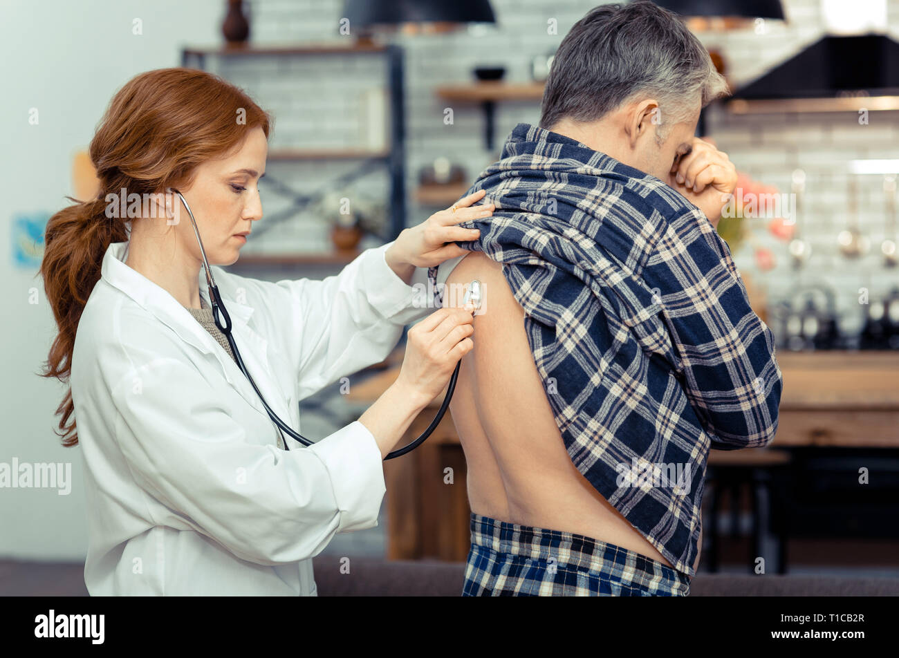 Nice serious doctor using her professional stethoscope Stock Photo - Alamy