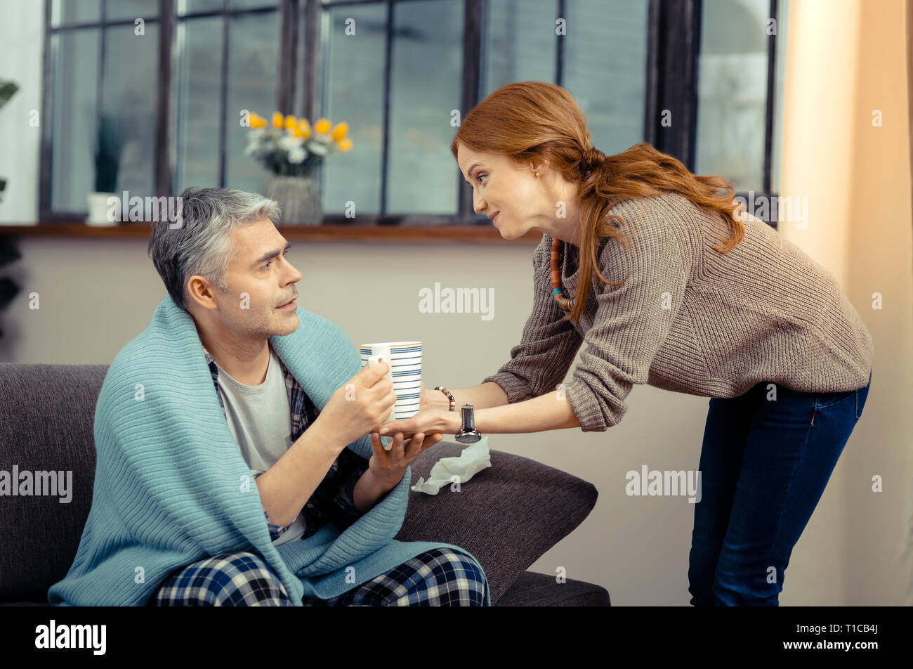 Positive cheerful woman bringing tea for her husband Stock Photo - Alamy