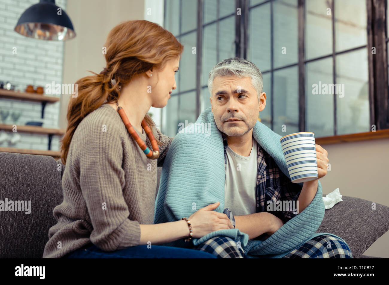 Nice caring wife supporting her ill husband Stock Photo - Alamy