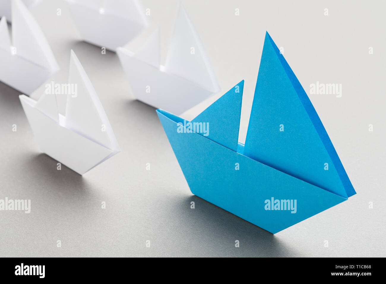 Blue paper boat leading white ships, panorama Stock Photo - Alamy
