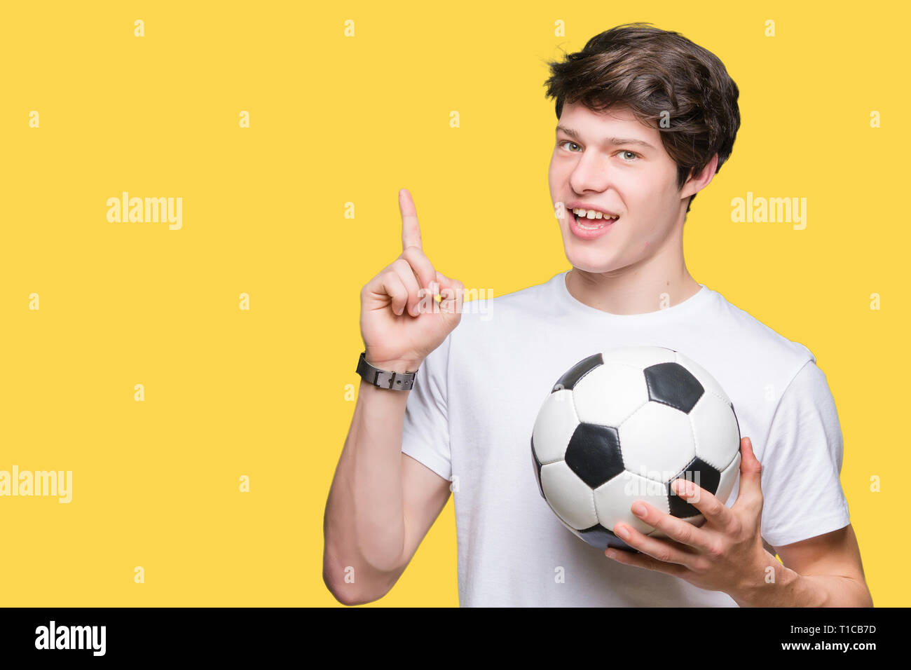 Young man holding soccer football ball over isolated background ...